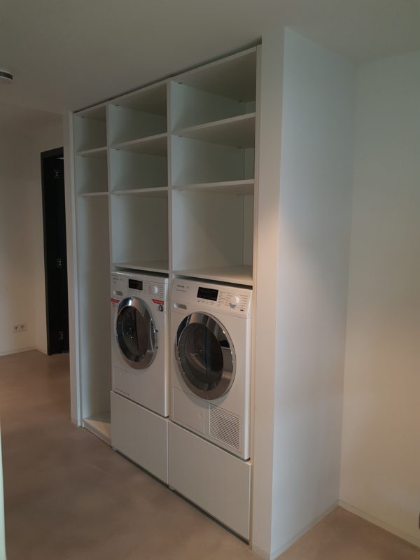 Een opgeruimde wasruimte met een wasmachinekast